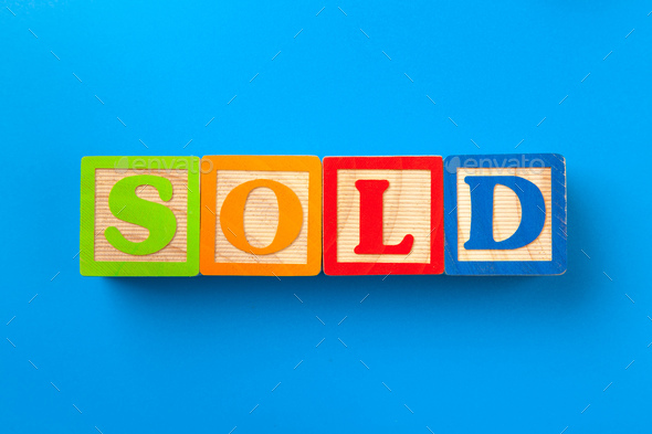 Sold. Wooden colorful alphabet blocks on blue background, flat lay, top ...