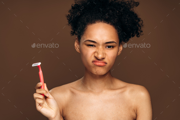 Horizontal view of sad young woman looking at the razor with ...