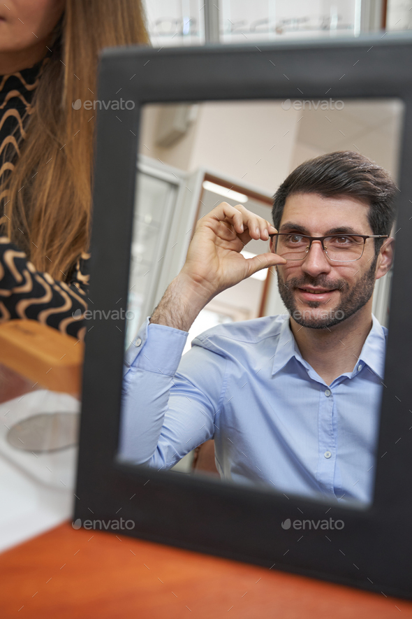 Man checking his appearance with glasses in a mirror Stock Photo by ...