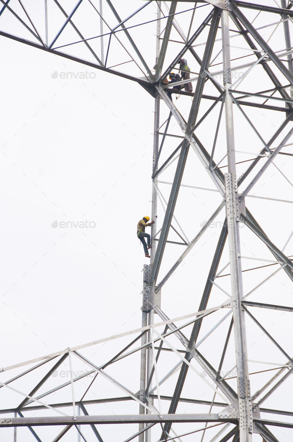 Pylon construction workers working on the top of power tower. Stock ...