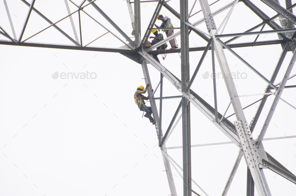 Pylon construction workers working on the top of power tower. Stock ...