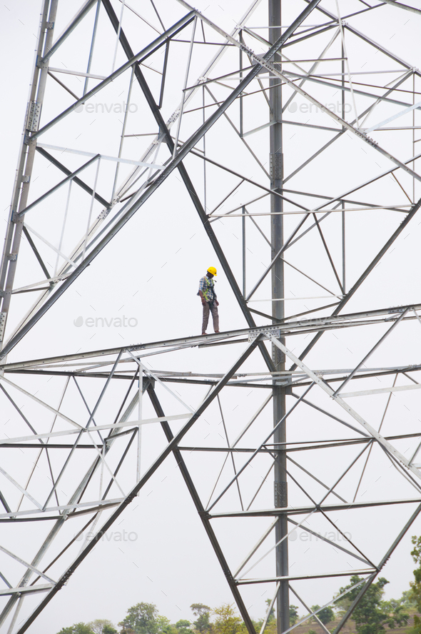 Pylon construction workers working on the top of power tower. Stock ...