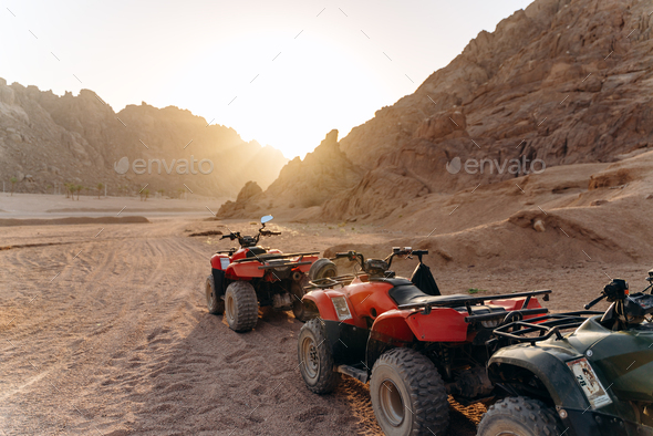 Column of ATVs in the desert at sunset. Sunny desert Stock Photo by ...