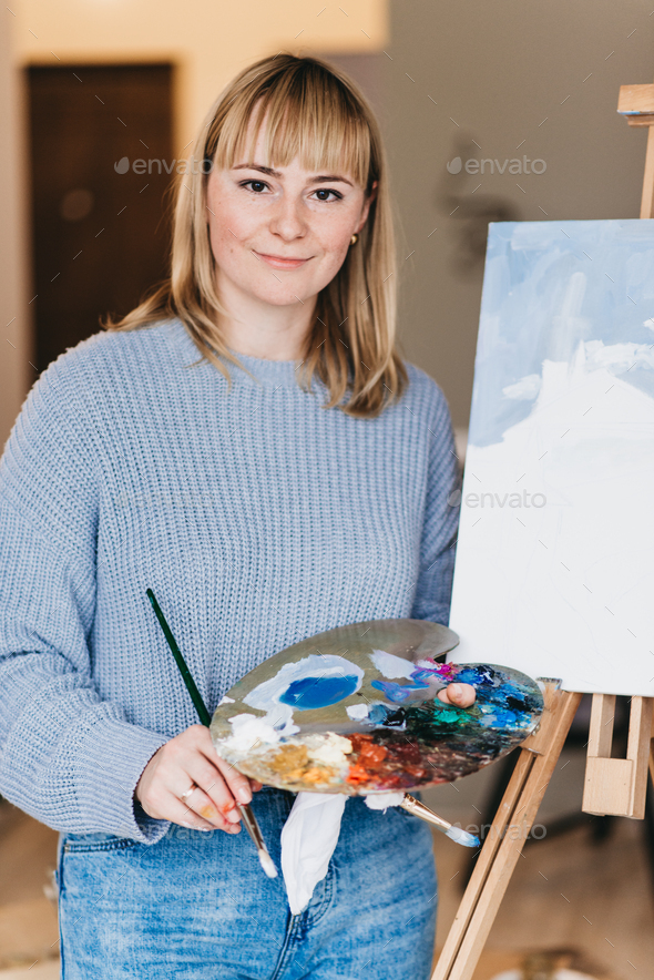 Portrait of a gorgeous female artist working on art project on her ...