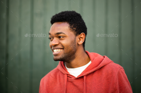 Close up happy young black man looking away against green background ...