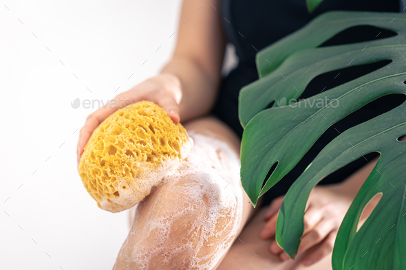 Young woman washing legs with yellow sponge and soap foam. Stock Photo ...