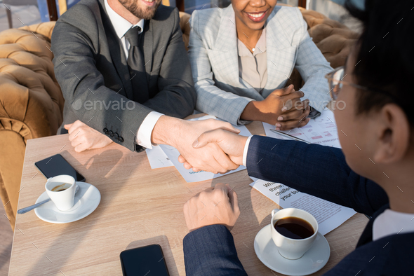 Handshake of two successful business partners over table with papers ...
