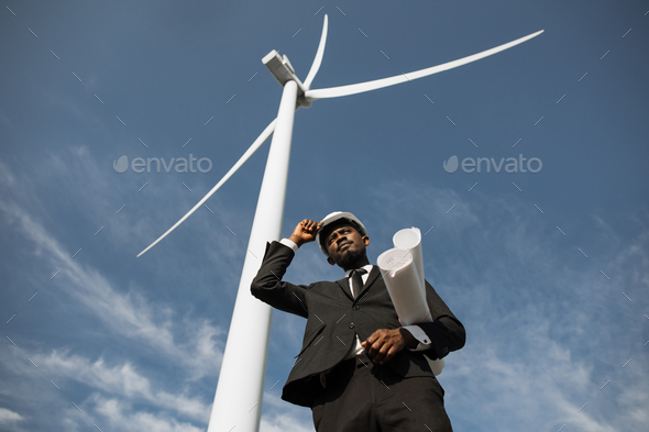 Man in suit standing among windmills with blueprints Stock Photo by ...