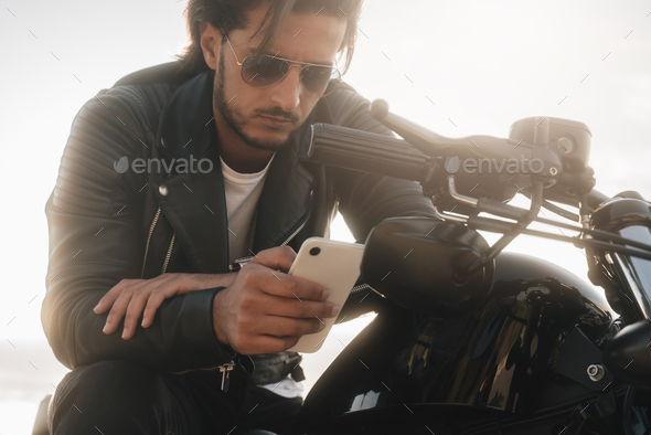 Biker holding his phone, using app to find the best route, sitting on ...