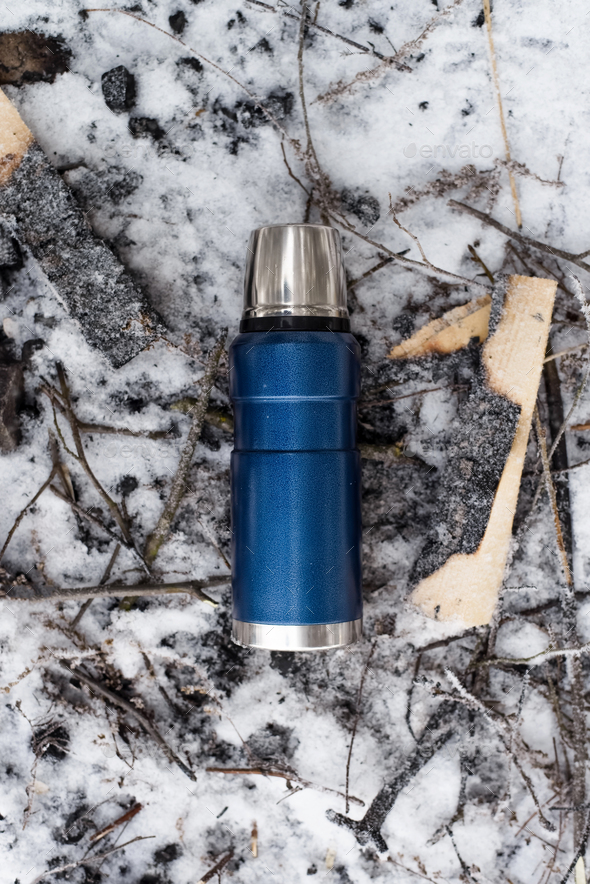 Vacuum travel thermos outside. Winter forest and coals, top view ...