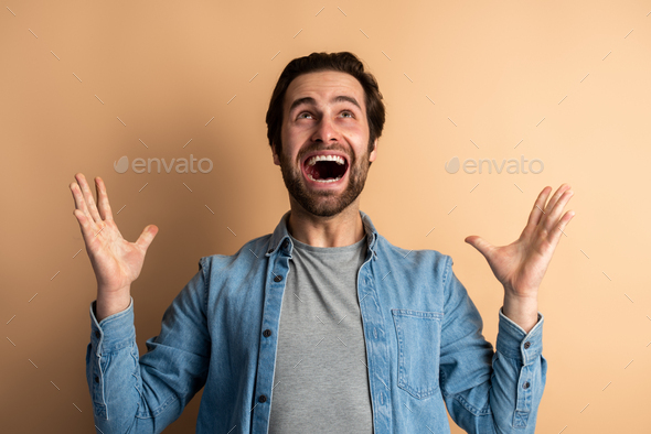 Overjoyed handsome man expressing winning gesture with raised fists and ...