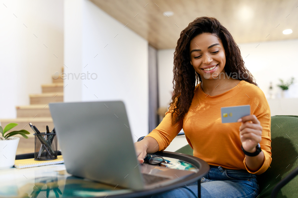 Happy woman holding debit credit card, using pc Stock Photo by Prostock ...