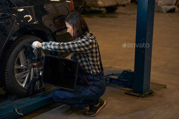 Capable brunette lady fixing a car tyre at service station Stock Photo ...