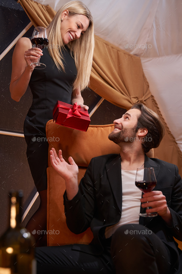 Female passing gift box to her partner in armchair Stock Photo by Iakobchuk