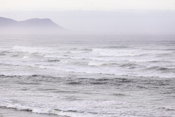 View over a sandy beach, mist rising and waves breaking on the Atlantic ...