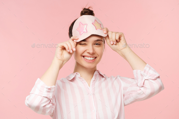 Girl wearing eye mask for sleeping, keeping it on forehead and winking ...