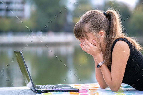 Exhausted young woman working behind laptop computer lying down in ...