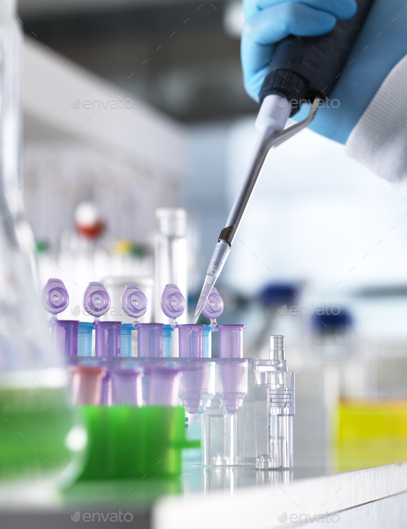 Cropped hand of scientist pipetting DNA samples into vials for ...