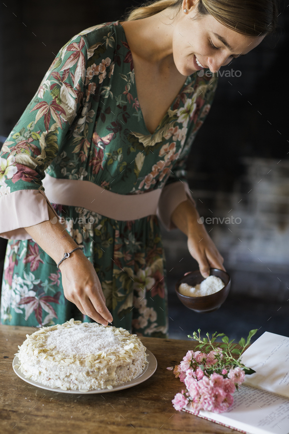 Smiling young woman garnishing home-baked cake Stock Photo by westend61