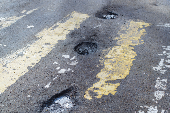 Pits on the road, destroyed asphalt, erased markings of a pedestrian ...