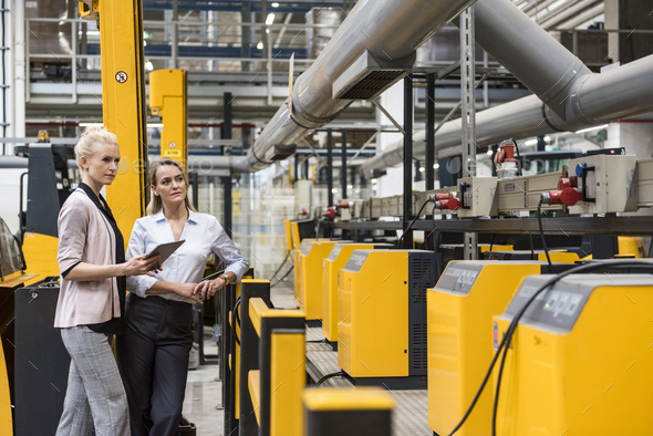 Two women with tablet looking at machine in factory shop floor Stock ...
