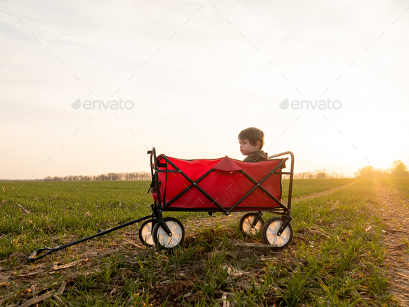 Little boy sitting in a wagon in a country road in sunset Stock Photo ...