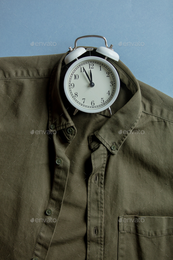 Vintage alarm clock and green shirt on gray background Stock Photo by ...