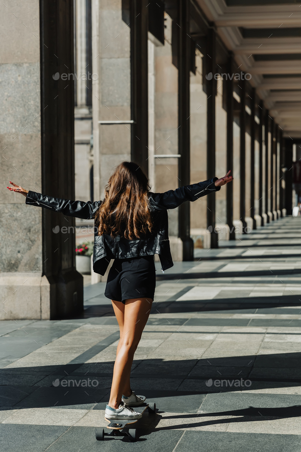 Beautiful young skater woman riding on her longboard in the city. Stock ...