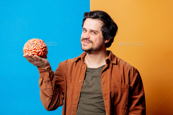 Guy in shirt hold human brain on yellow and blue backgrounds Stock ...