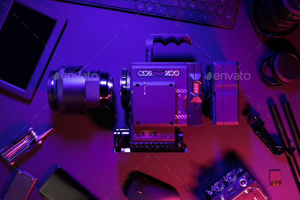 Overhead view of cinema camera and computer parts on colorful ...