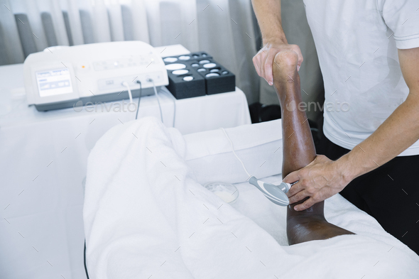 The physiotherapist treating a man using equipment for radio therapy ...