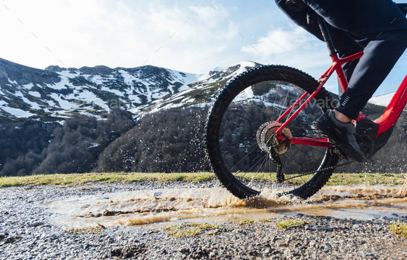 Man riding a mountain bike passing a puddle of water Stock Photo by ...
