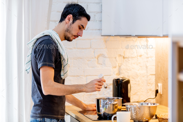 Young man in black shirt cooking at kitchen in home. Stock Photo by ...