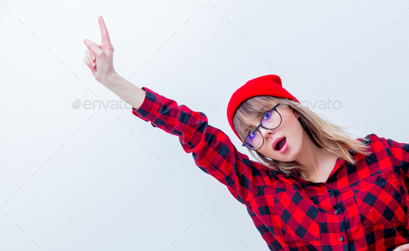 Young woman in red shirt and hat pointing with finger Stock Photo by ...