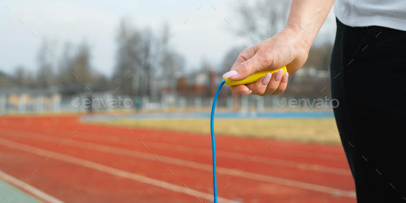 Athlete trains in the stadium with a skipping rope. Female hand holding ...