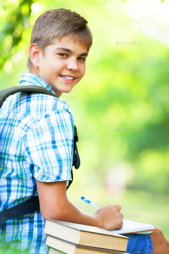 Teen boy with books and notebook at outdoor. Stock Photo by Masson-Simon