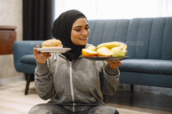 Arab woman choosing between healthy and unhealthy eating Stock Photo by ...