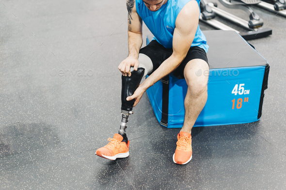Disabled athlete assembling his leg prosthesis in the gym. Paralympic ...