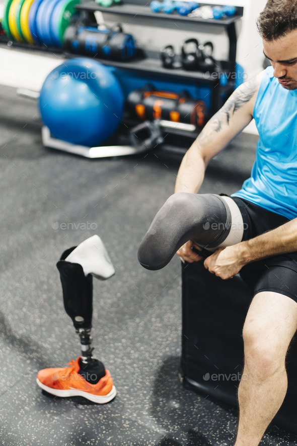 Disabled athlete assembling his leg prosthesis in the gym. Paralympic ...