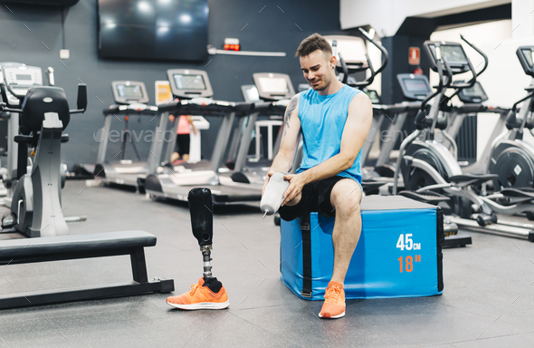 Disabled athlete assembling his leg prosthesis in the gym. Paralympic ...