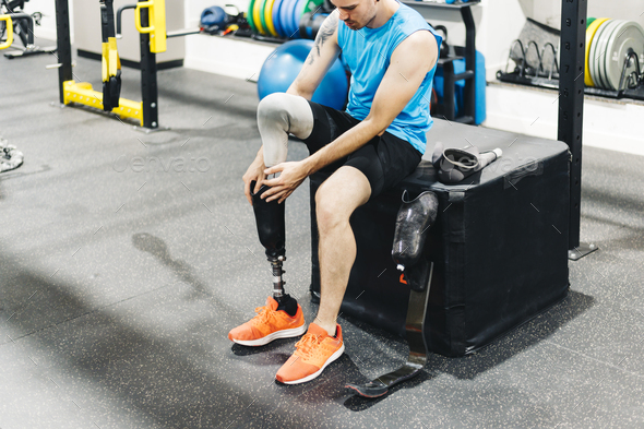 Disabled athlete assembling his leg prosthesis in the gym. Paralympic ...