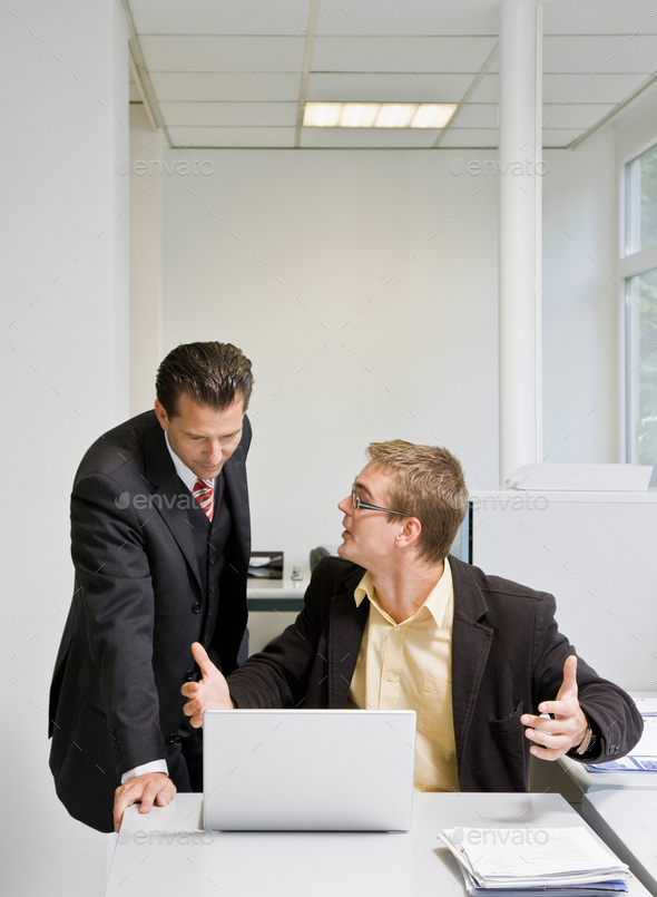 Boss looking at laptop with co-worker Stock Photo by ImageSourceCur
