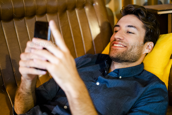 Man lying on couch using cell phone Stock Photo by westend61 | PhotoDune