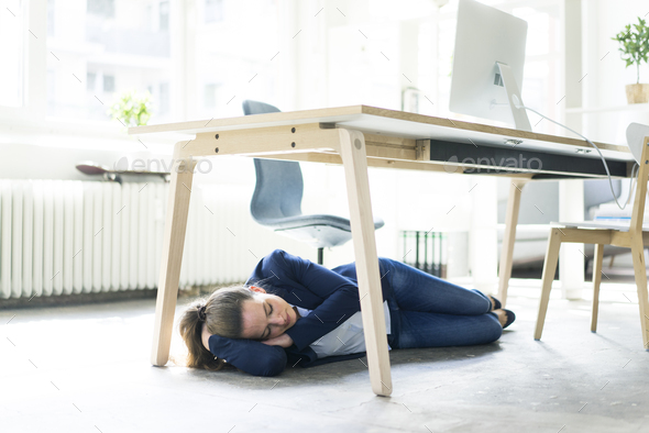 Businesswoman lying under the table in office sleeping Stock Photo by ...