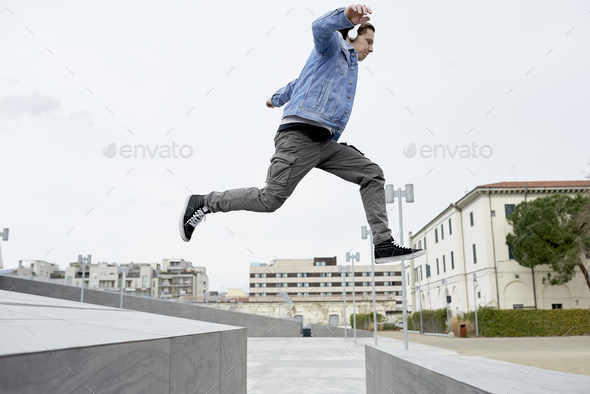 Young man jumping over gap between walls, mid air Stock Photo by westend61