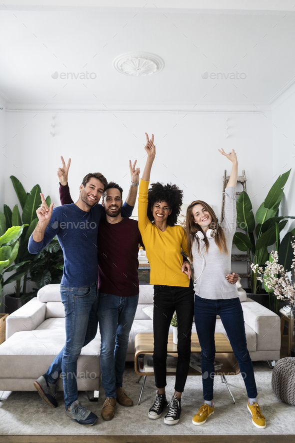 Portrait of four happy friends standing side by side in living room ...