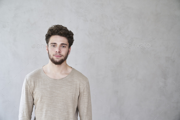 Portrait of confident young man in front of grey wall Stock Photo by ...