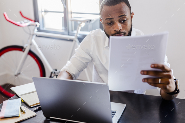 Man looking at papers at desk in home office Stock Photo by westend61