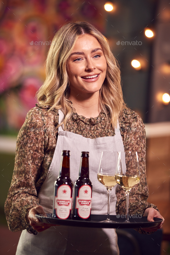 Portrait Of Smiling Female Server Holding Tray Of Drinks In Cool Bar Or ...