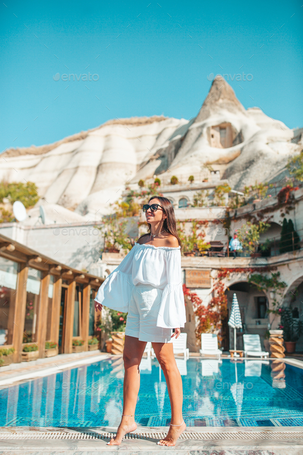 Beautiful woman in white clothes posing near swiming pool in Cappadocia ...